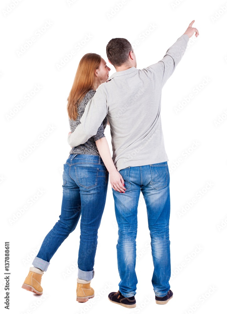 young couple pointing at wal Back view (woman and man). Rear view ...