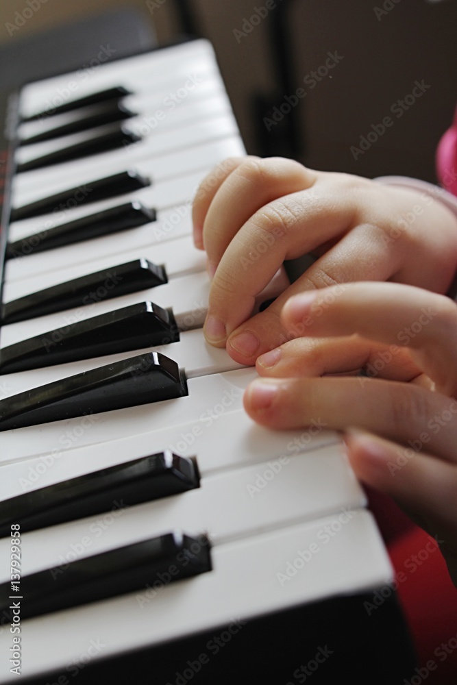 Small kid hands playing notes on MIDI keyboard with miniature keys ...