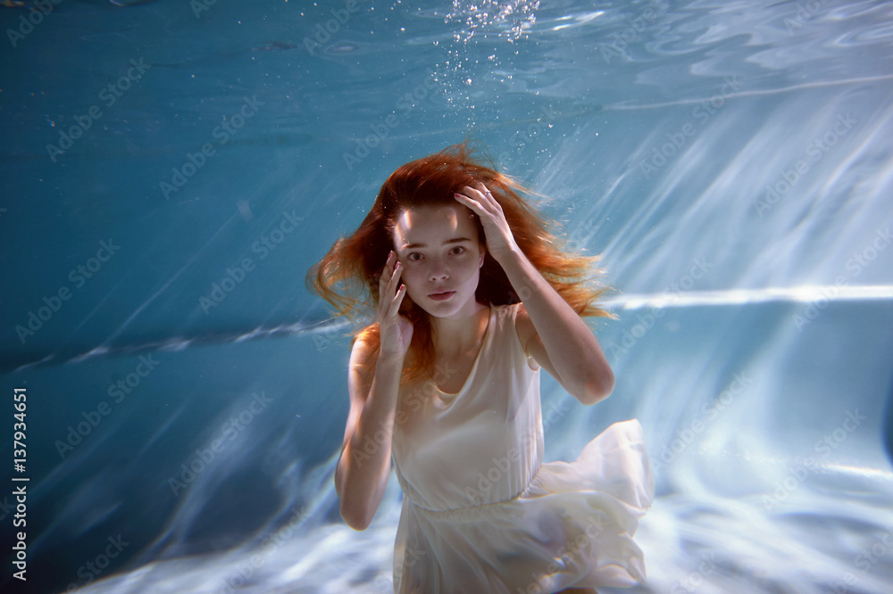 Underwater in the pool with the purest water. Beautiful girl in a ...