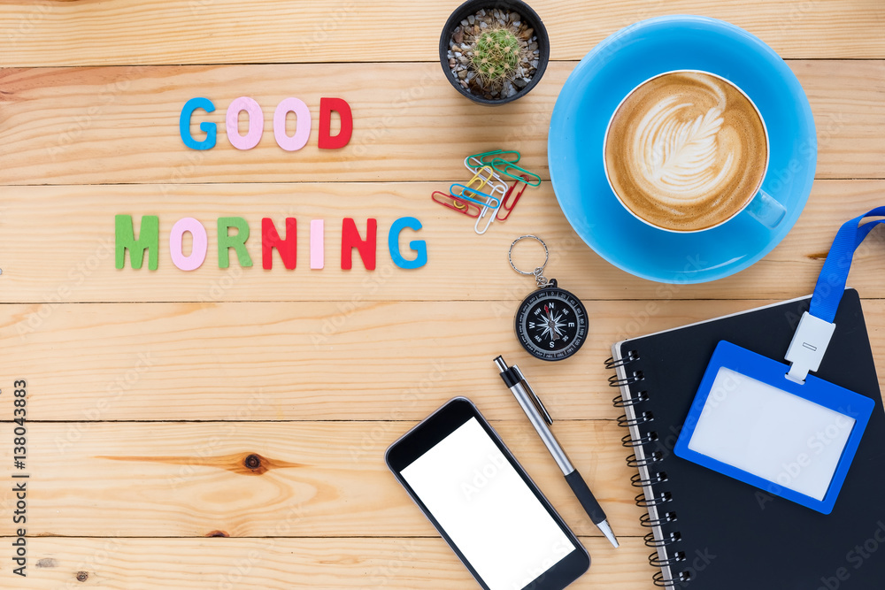 Caption word Good morning. Office desk with notebook, pen, smart phone ...