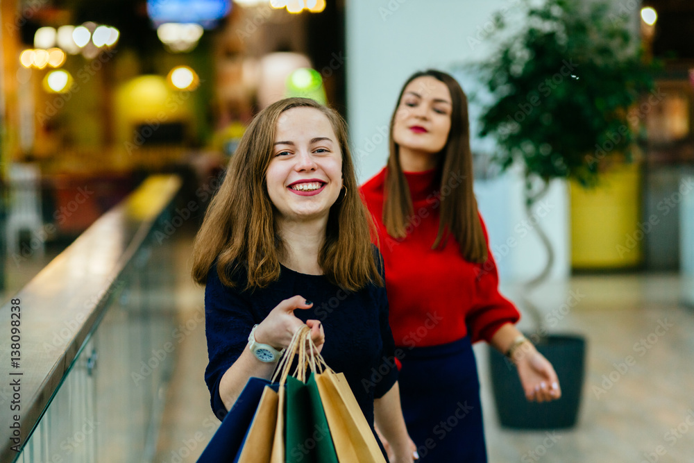 Front view of two girls of shoppers running in the shopping center ...