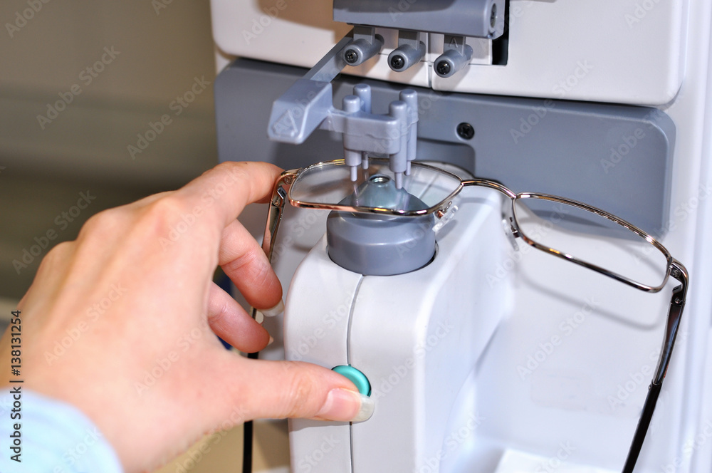 Female optician measuring and preparing glasses on the latest digital ...