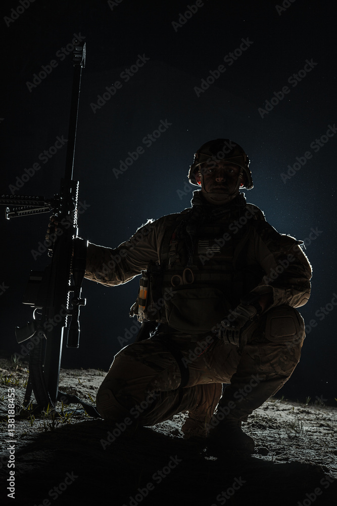 Army sniper with big rifle sitting holding rifle on black background ...