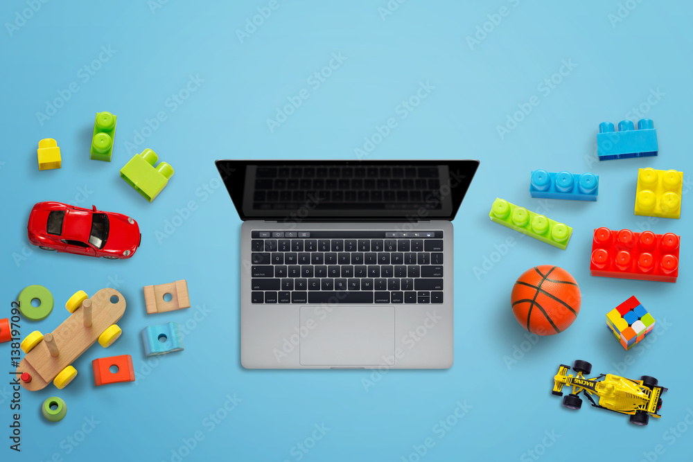 Laptop computer and kid toys on blue desk. Top view. Blank display for ...