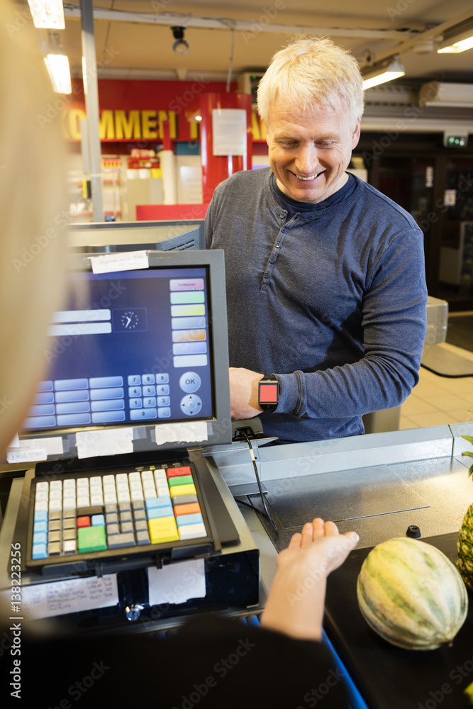 Customer Paying Through Smartwatch While Female Cashier Guiding Stock ...