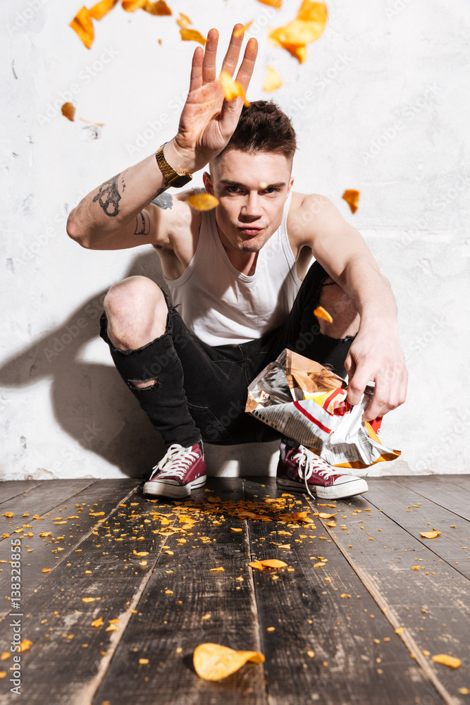 Irritated young man throwing potato chips out from packet Stock Photo ...