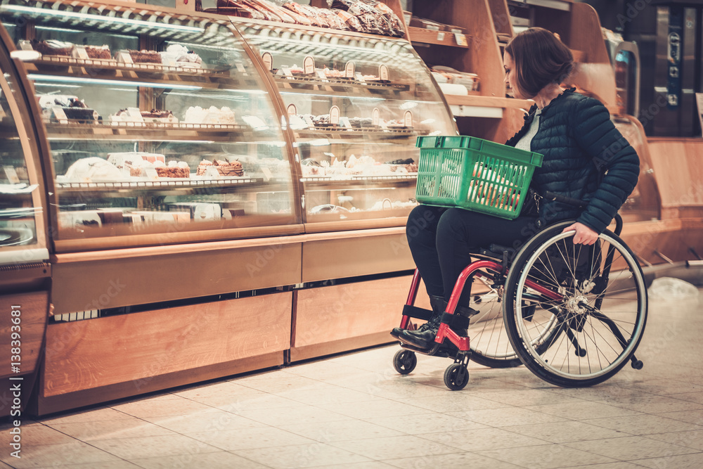 Disabled woman in a wheelchair in a grocery store Stock Photo | Adobe Stock