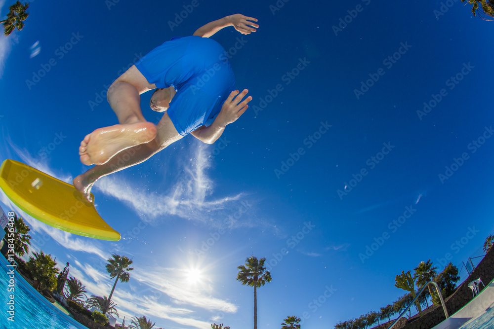 boy has fun jumping with the surfboard in the pool Stock-Foto | Adobe Stock