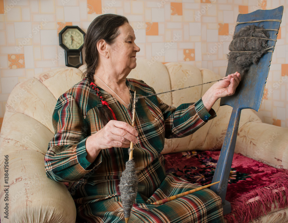 Very old woman Granny old homemade wooden spinning wheel twists the ...
