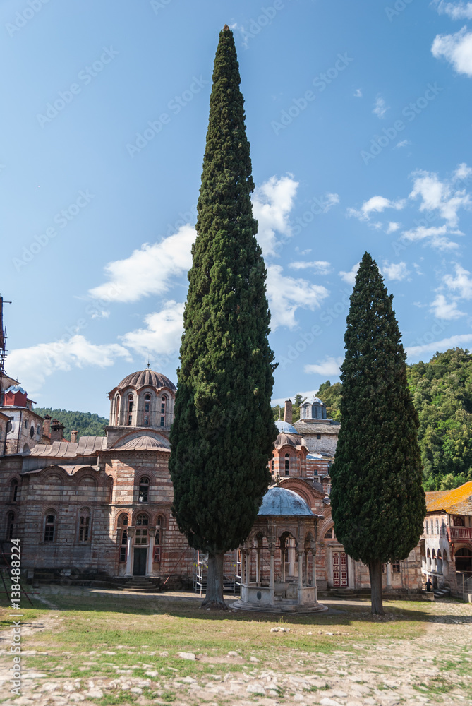 Ancient orthodox monastery courtyard with two cypress trees in front ...