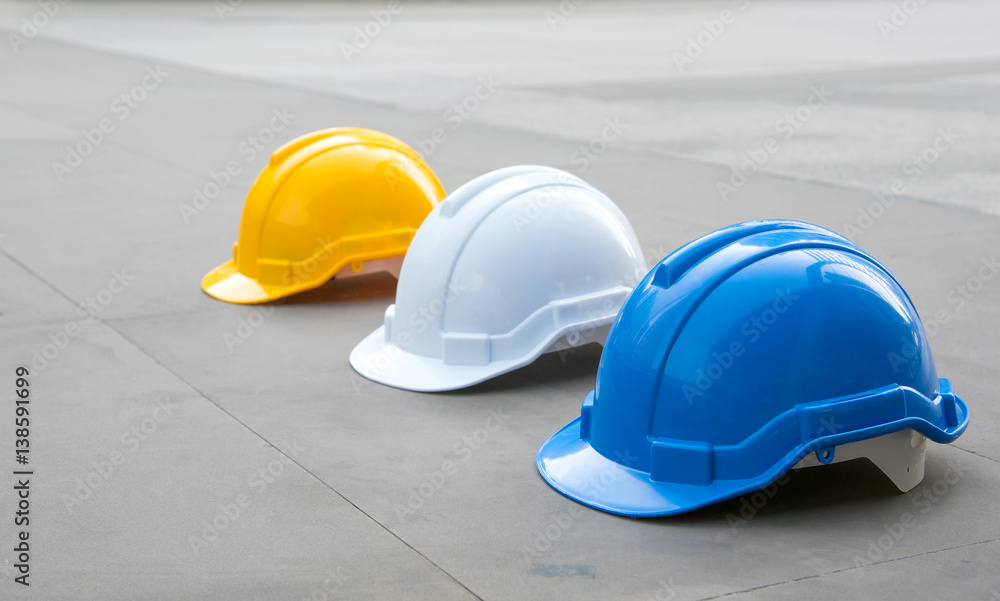 Tree safety plastic helmets : white, yellow and blue on concrete floor ...