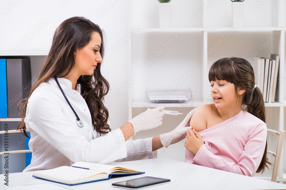 Female doctor giving injection to a scared child at medical office ...