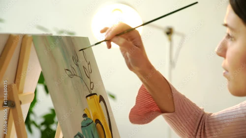 Pretty smiling young woman drawing a picture with poster paint. Front ...