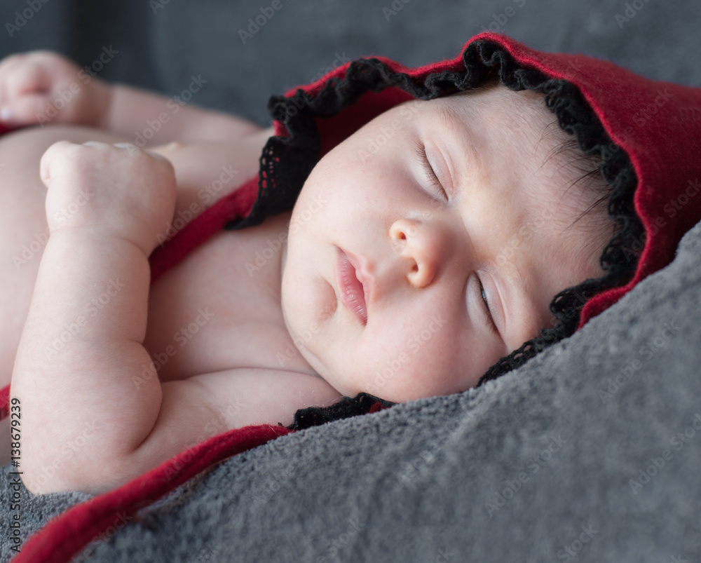 Newborn baby closeup in a red cap. Close-up portrait of a beautiful ...