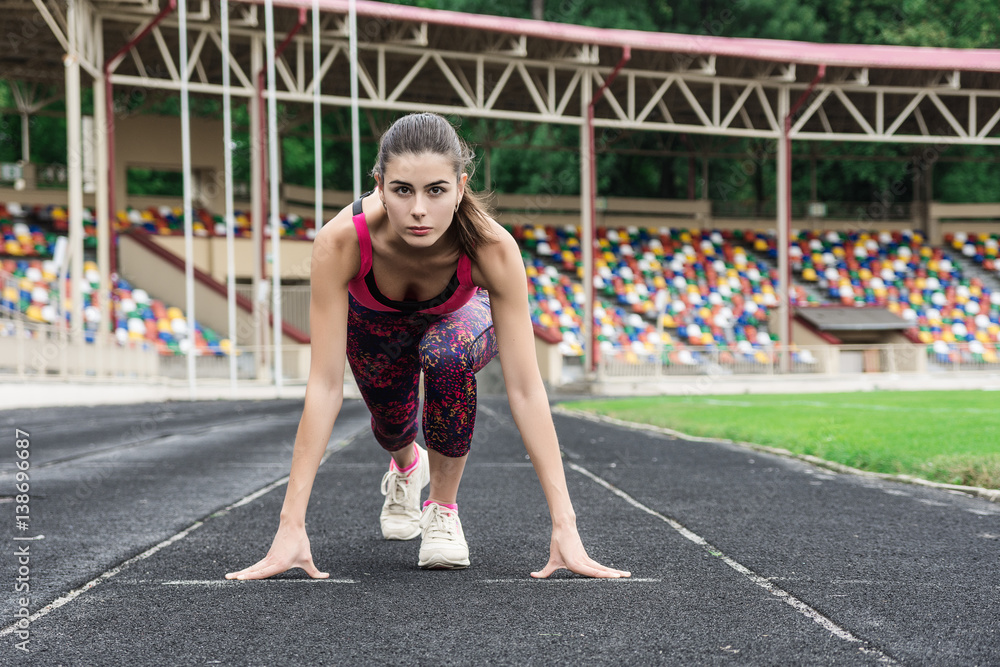 Young woman athlete at starting position ready to start a race. Female ...