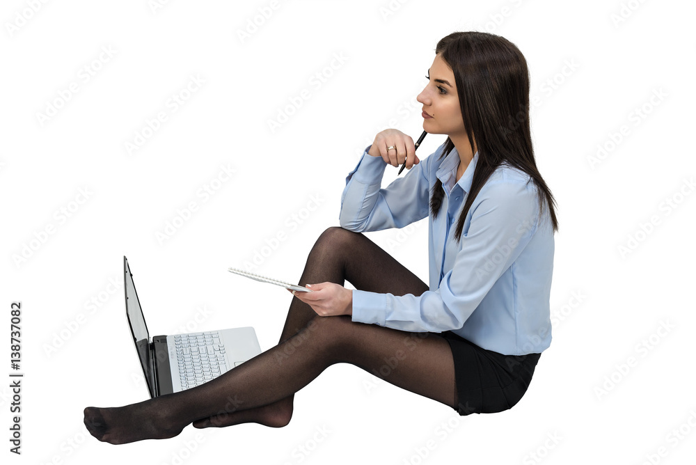 Pretty woman is sitting on the floor with a laptop, pen and notepad ...