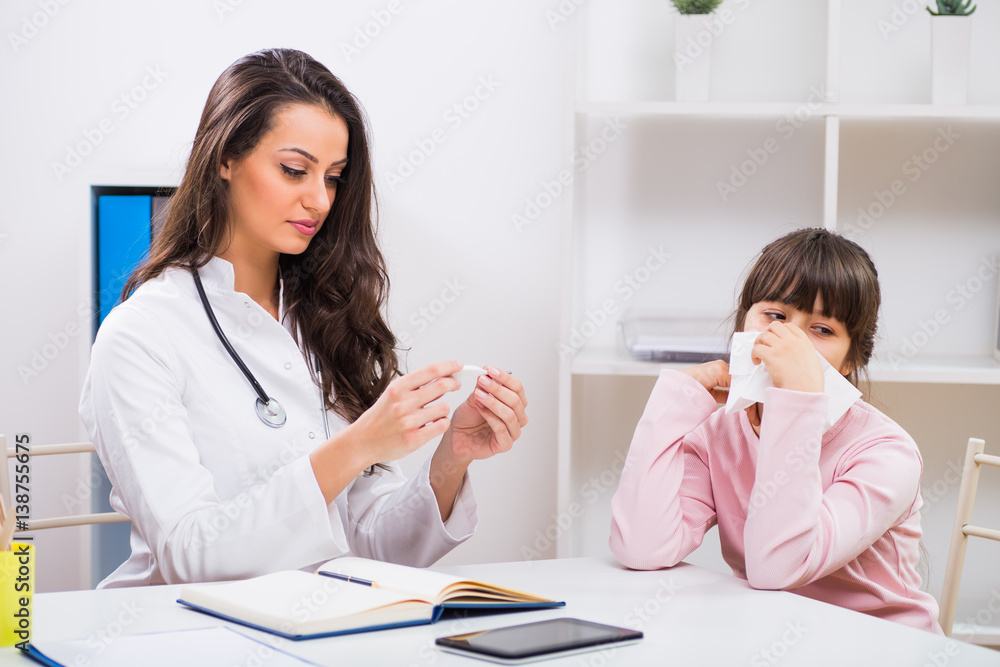 Female doctor checking temperature of sick child at medical office ...