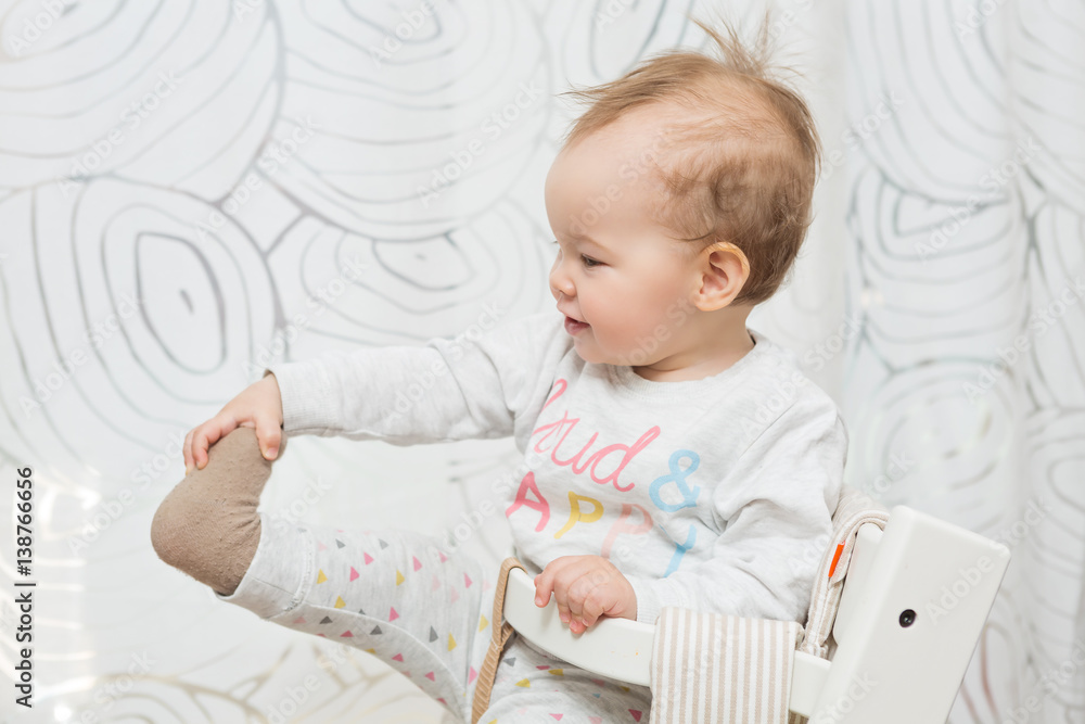 Eleven months old baby girl sitting in a stool, dragging her sock from her feet Stock Photo ...