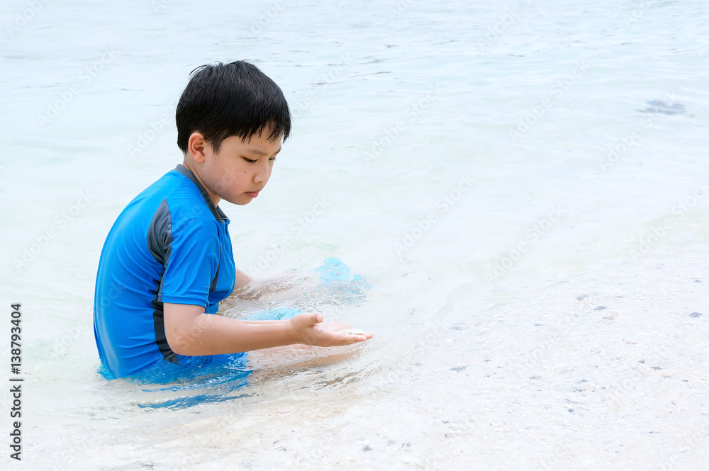 Asian little boy relaxing on a beautiful tropical beach enjoying on a ...