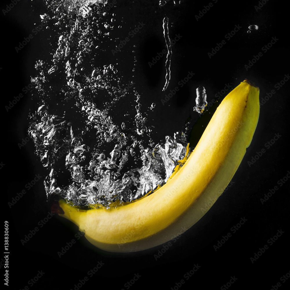 Yellow banana falling into the water with splashes and bubbles. Healthy ...