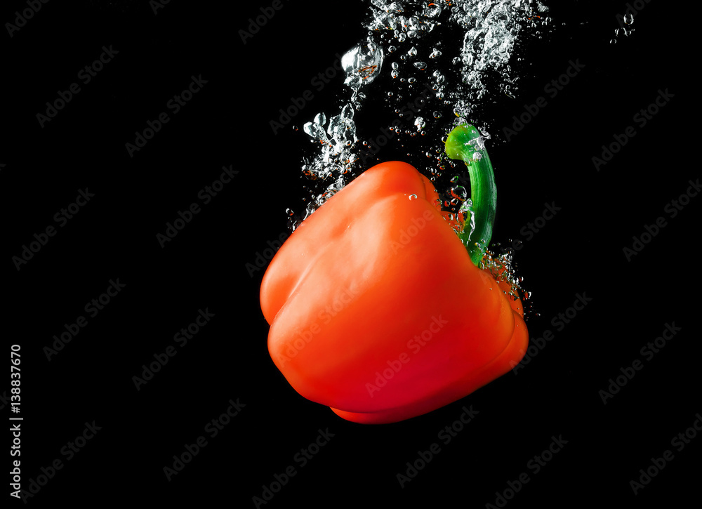 Red paprika pepper falling into the water with a splash and air bubbles ...
