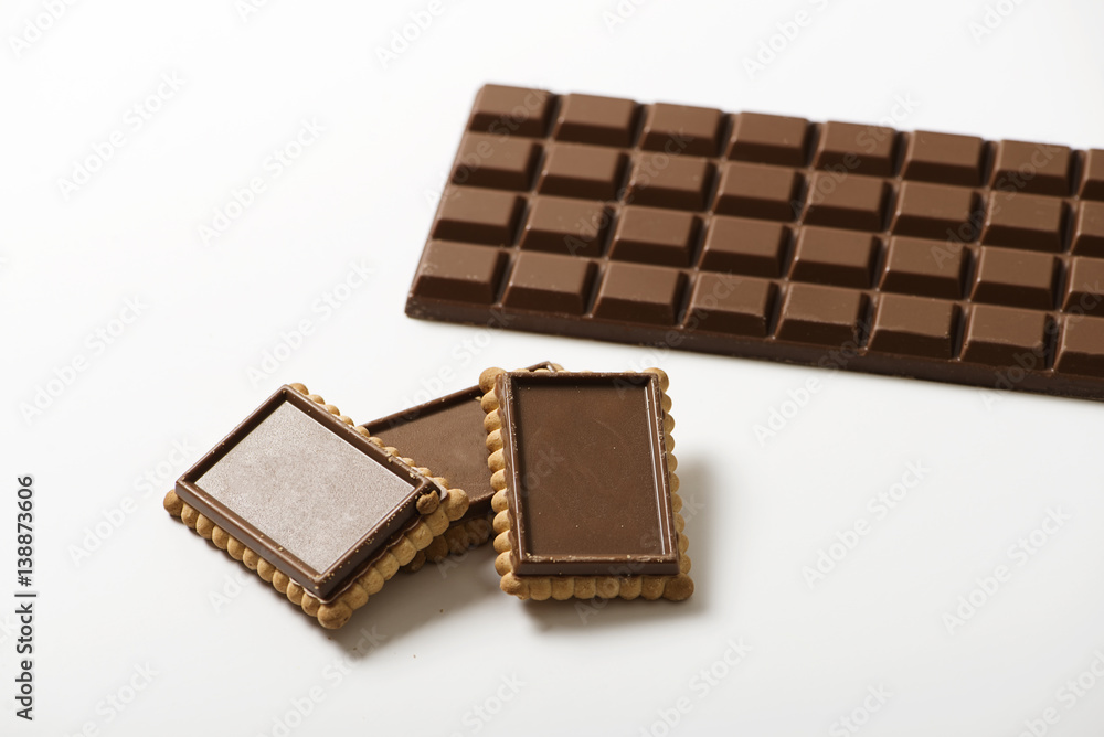 Various chocolate covered cookies next to chocolate tablet on white ...