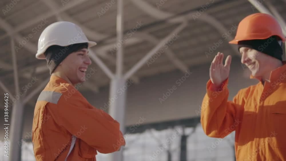 Two construction workers high five. They look very happy. New ...