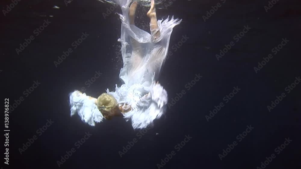 Underwater model free diver in costume angel swims in clean water in ...