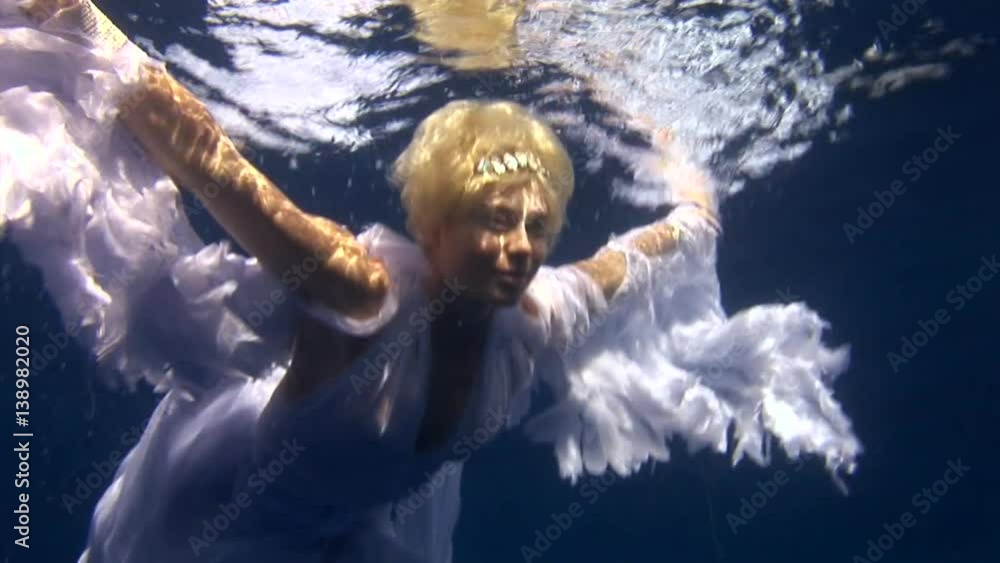 Underwater model free diver in costume angel swims in clean water in ...