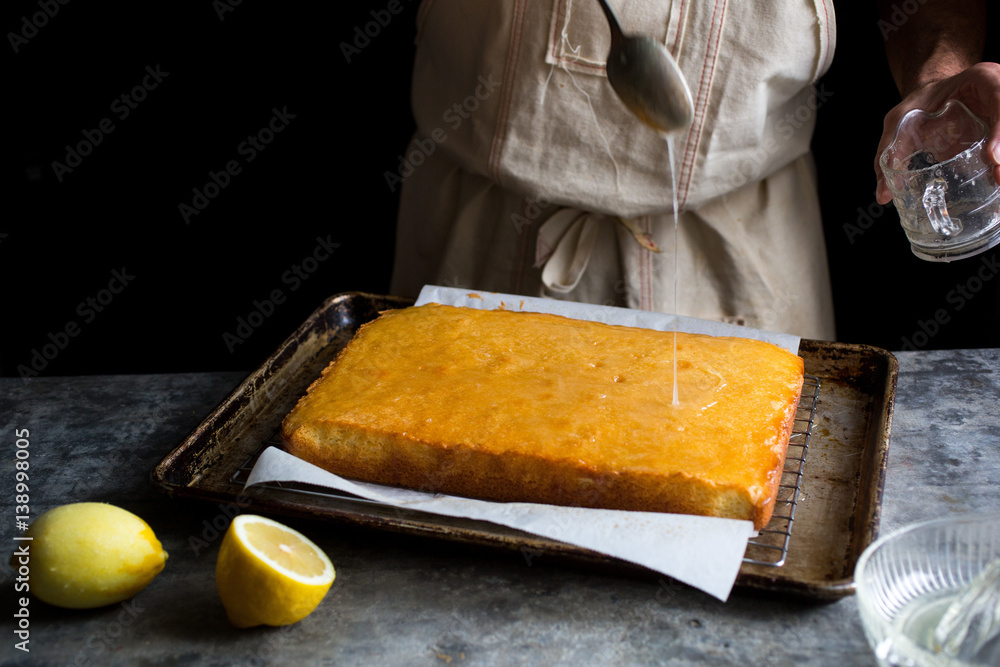 Person drizzling syrup onto lemon drizzle cake Stock Photo | Adobe Stock