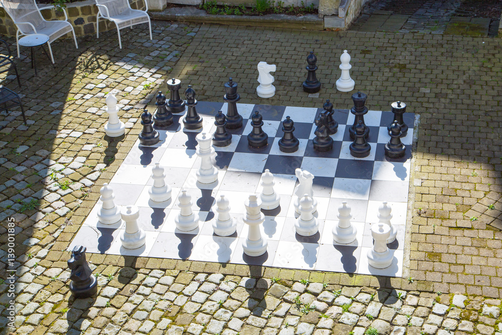 Chessboard made of concrete panels. Plastic large chess pieces on the ...