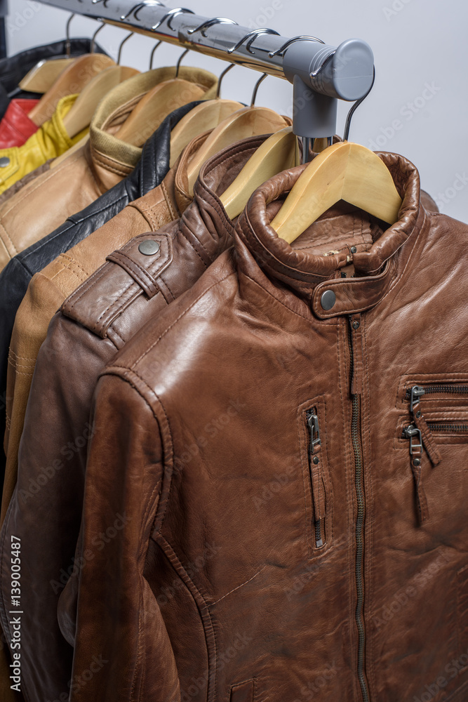 Different color leather jacket hanging on rack on white background ...