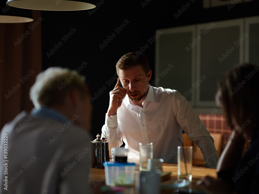 Mature man wearing white shirt talking on smartphone while standing at ...
