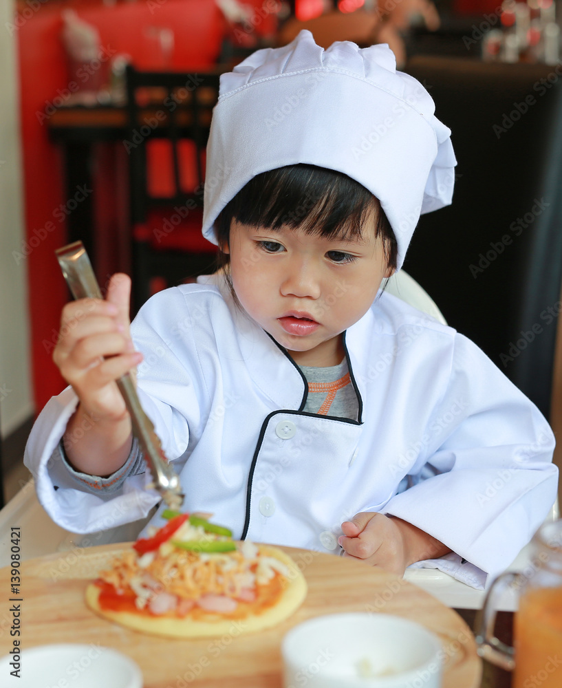 Kid girl in a suit of the little chef make mini pizza, Cooking child ...