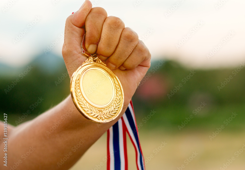 hand raised and holding gold medal against white background, award ...