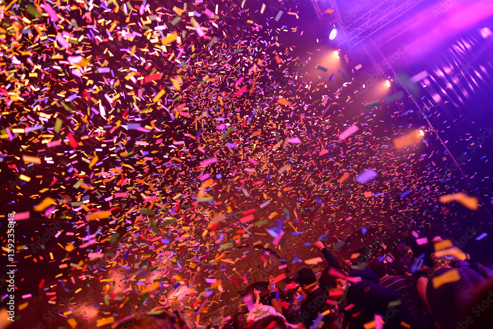 Confetti fired on air during a concert. People are happy and with hands ...