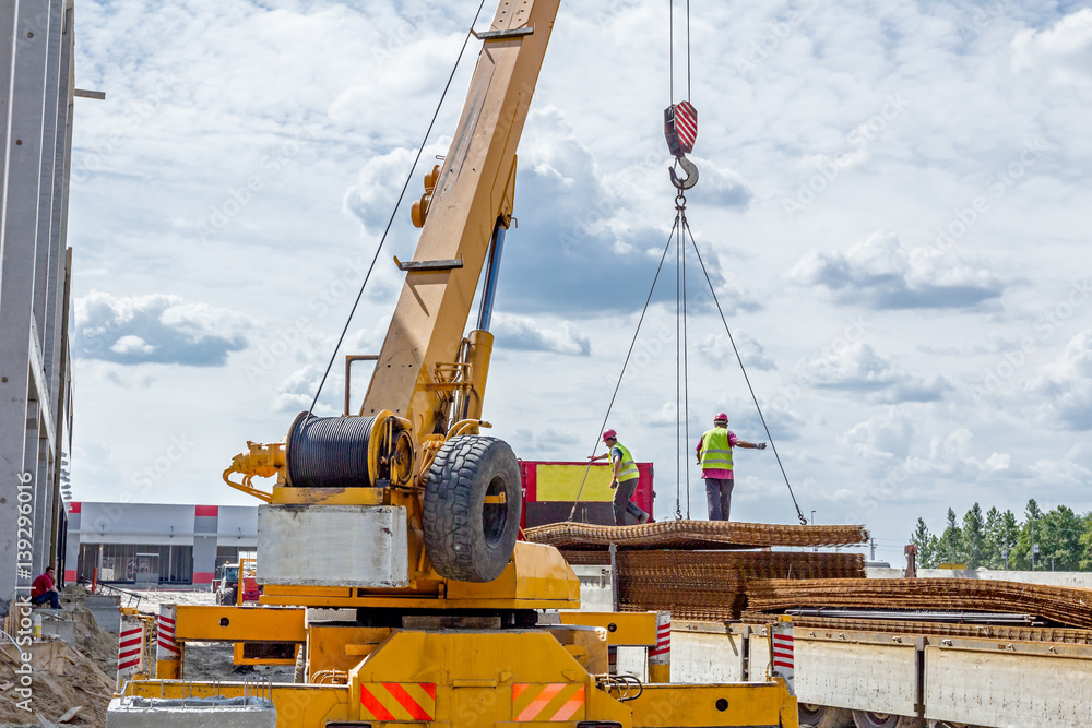 Mobile crane is carry pile of concrete armature, rusty square ...