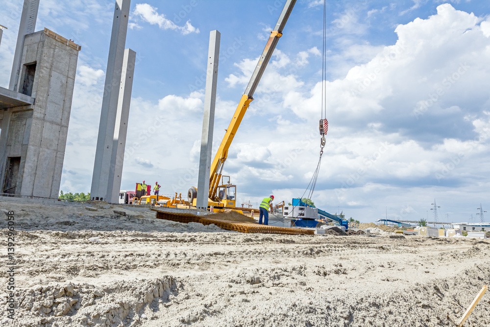 Mobile crane is carry pile of concrete armature, rusty square ...