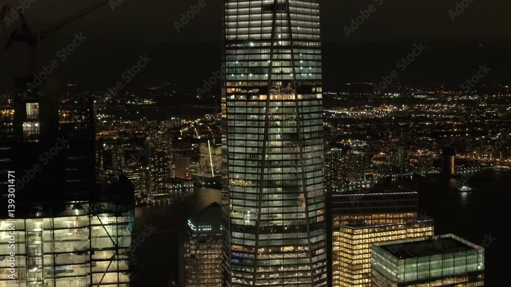 AERIAL HELI SHOT, CLOSE UP: Flying around scaffolded and lit building ...