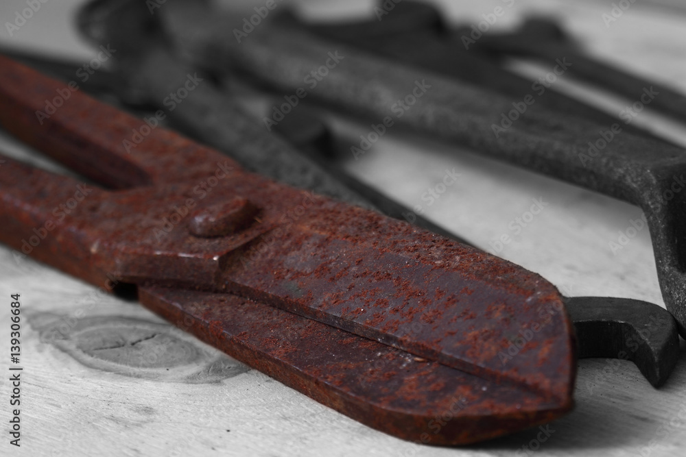Old rusty tin snips cutterwith spanners in the background with ...