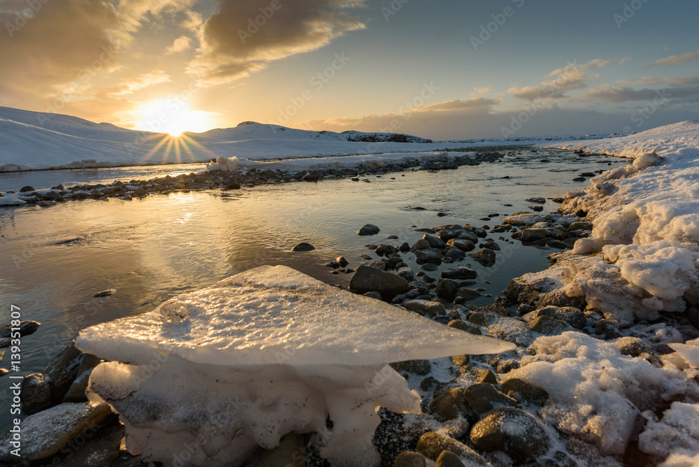 Sunrise over a river with an natural ice sculptur in the foreground ...