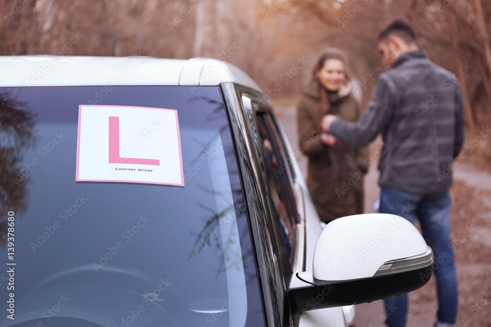 Learner driver sign on car windscreen. Blurred view of instructor and ...
