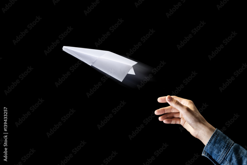Image of a hand is throwing white paper plane on black background ...