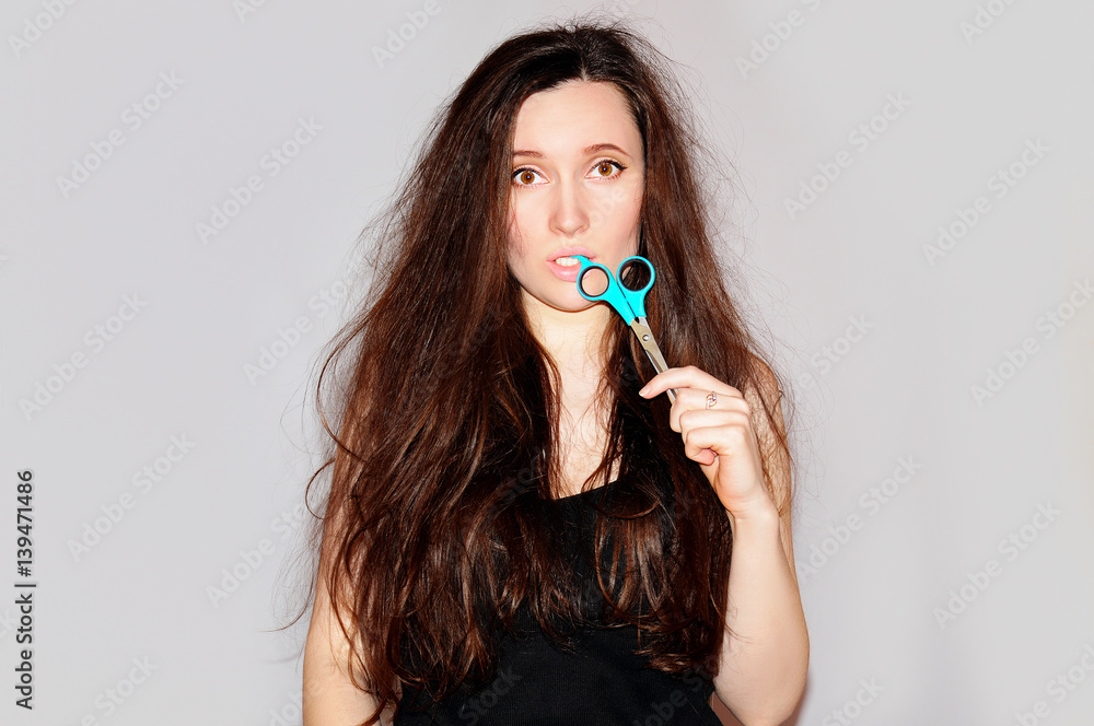Health and beauty. Beautiful young woman with scissors in hand looking ...