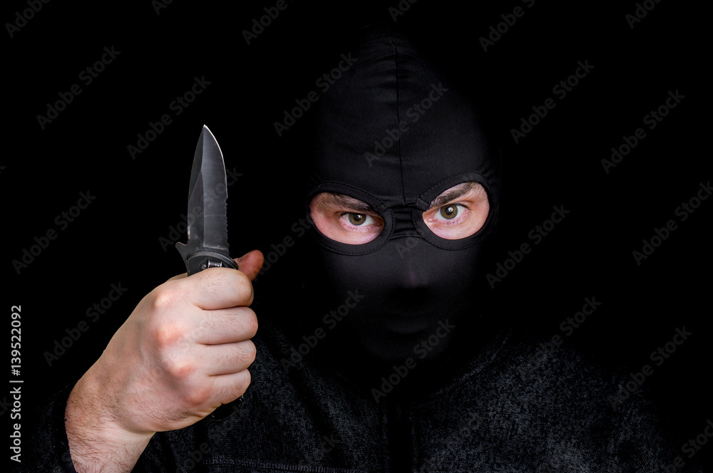 Portrait of man in mask holding knife against black background Stock ...
