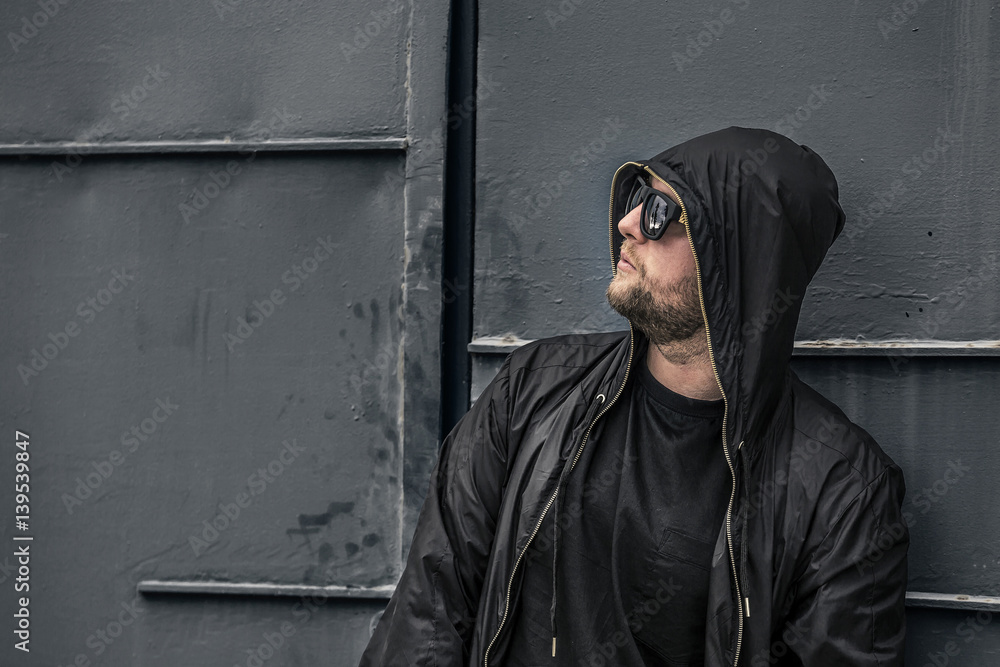 Conceptual photo of young and serious rapper in black zipped jacket and ...