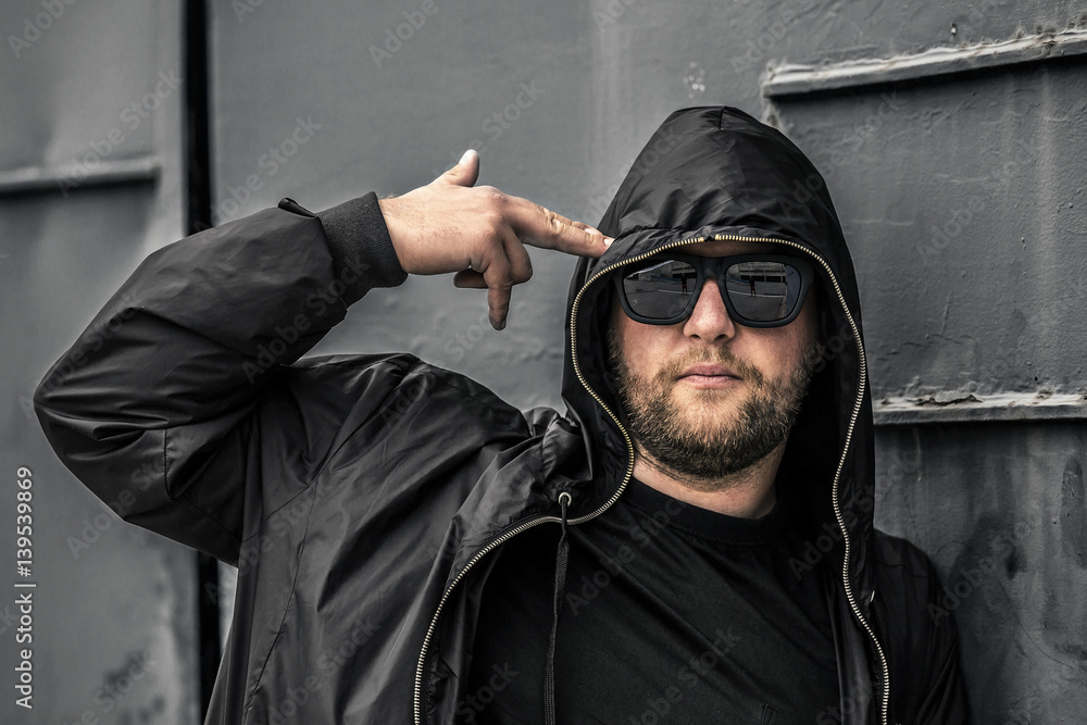 Conceptual photo of young and serious rapper in black zipped jacket and ...
