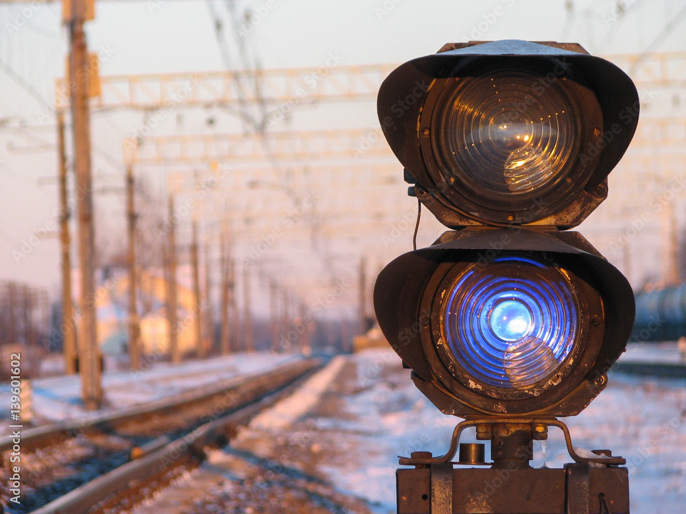 Railway traffic light shows blue signal on railway with blur effect and ...