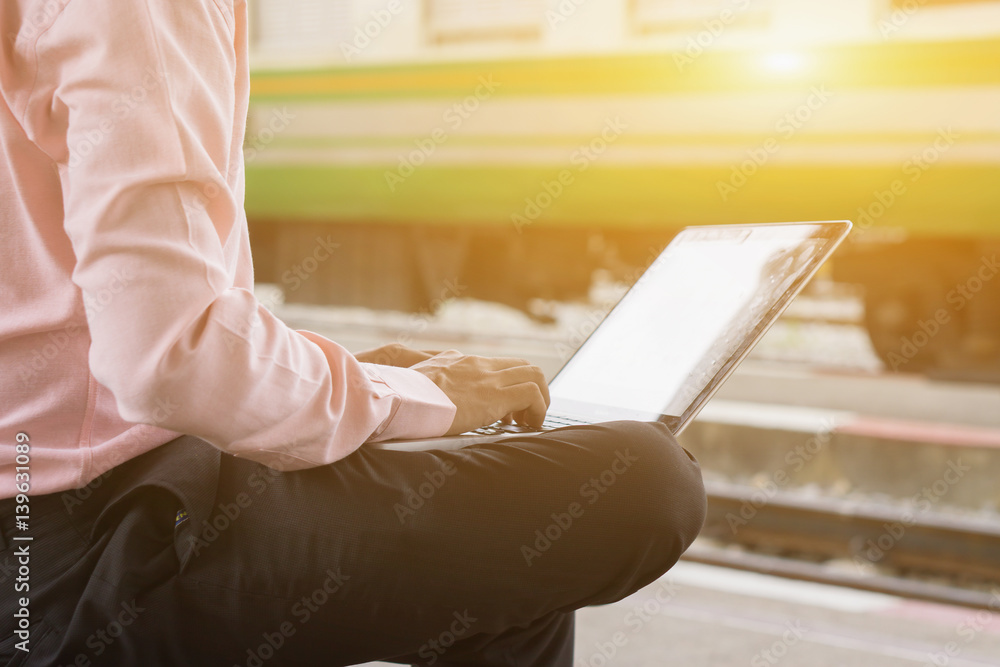 man using net-book,sitting in train station.modern businessman using a ...