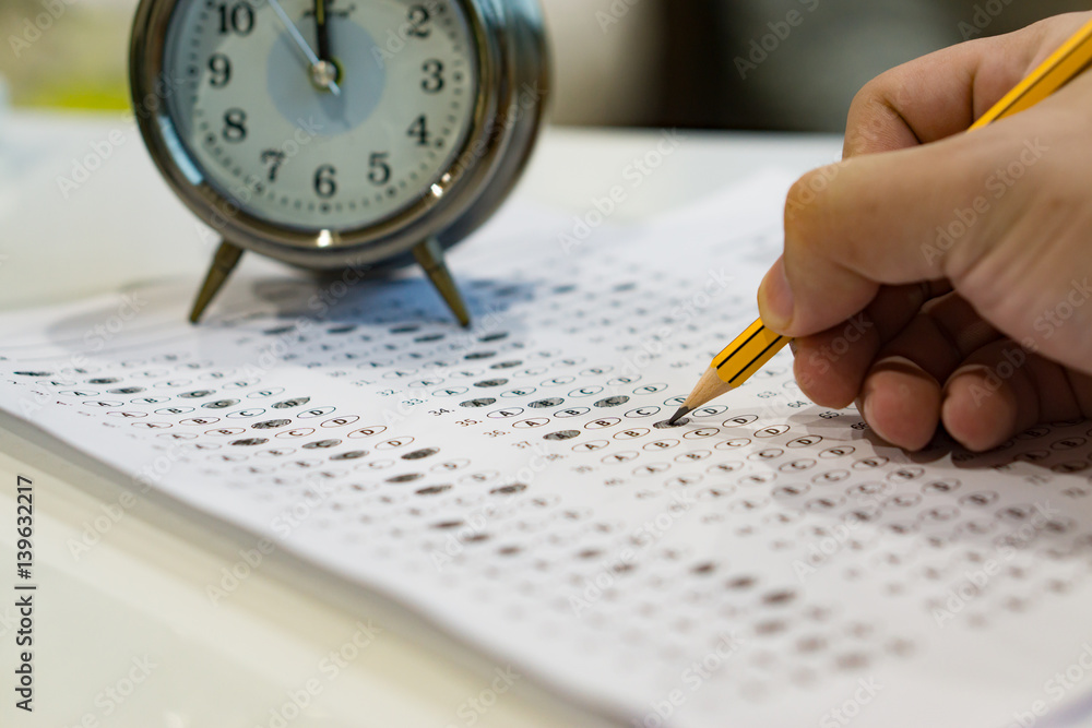 A pencil sitting on a test bubble sheet and alarm clock, optical form ...
